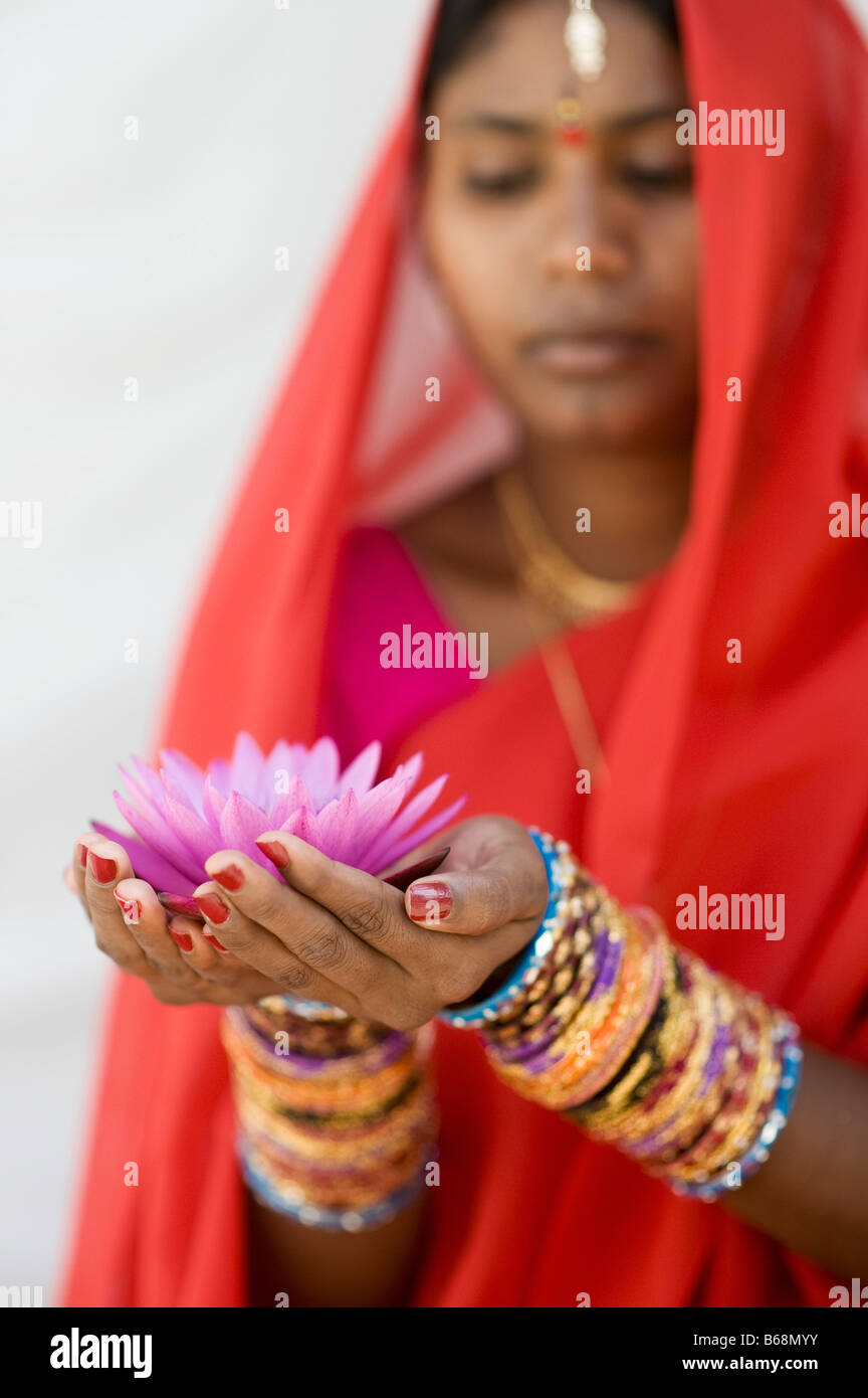 Indian woman offering a Nymphaea Tropical waterlily flower in a red ...