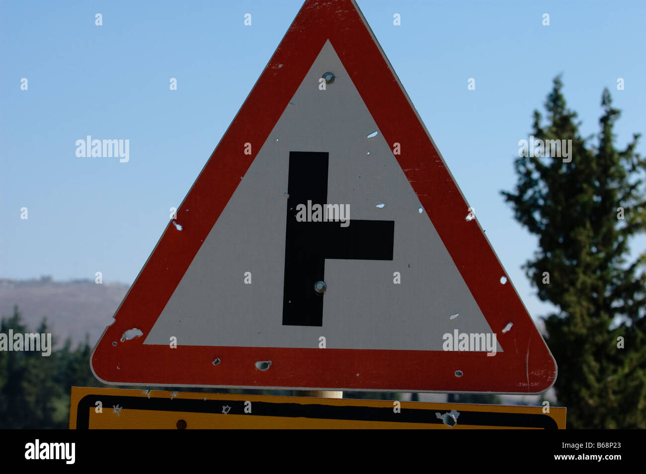 'side road' warning sign against Blue background with many holes in it ...