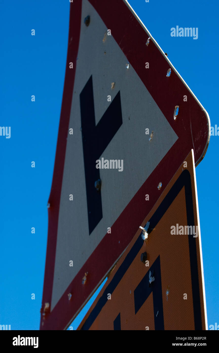 'side road' warning sign against Blue background with many holes in it ...