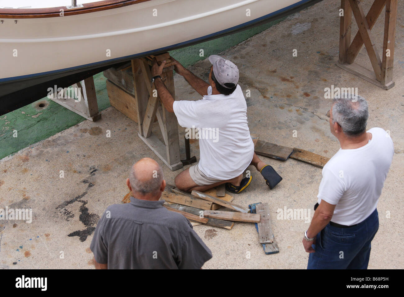Spanish workman chocking boat up out of the water for work in the ...