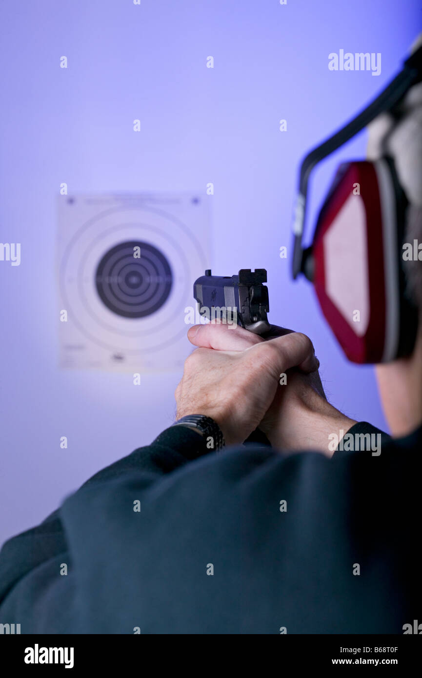 A shooter takes aim at a target with a handgun Stock Photo - Alamy