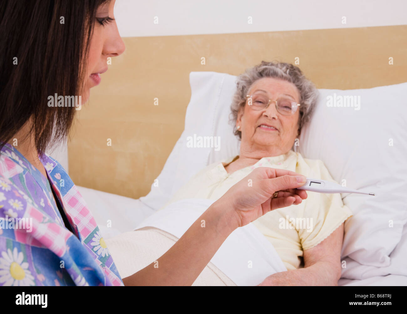 Nurse checking temperature on thermometer at female patients bed Stock ...