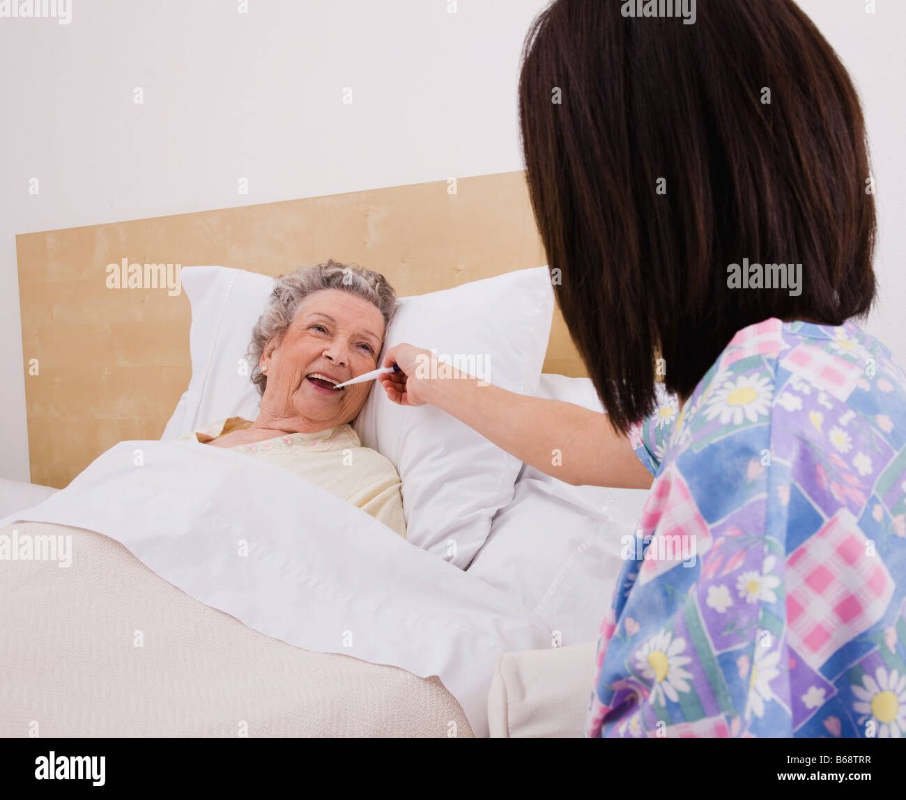 Nurse giving thermometer to female patient lying in bed Stock Photo - Alamy