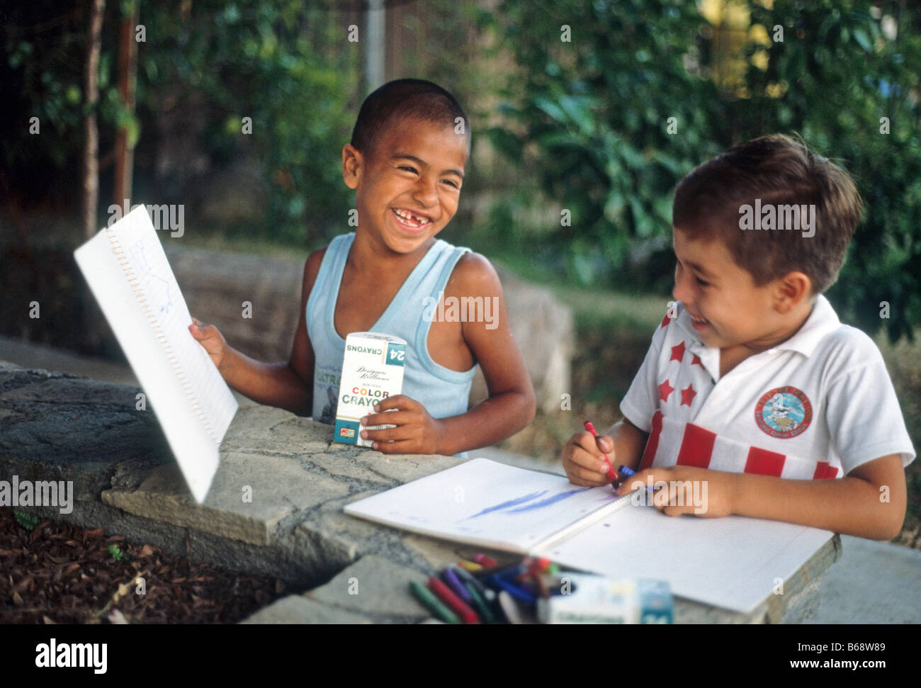 Two boys compare art and books at backyard table Stock Photo - Alamy