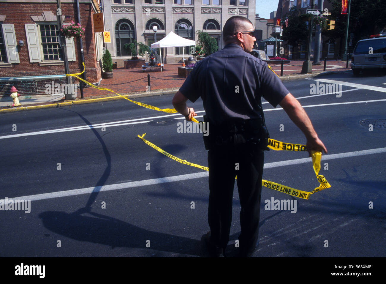 Police officer putting out crime scene tape Stock Photo - Alamy
