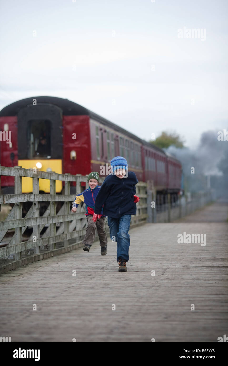 Two boys run alongside a train on a heritage railway line in ...