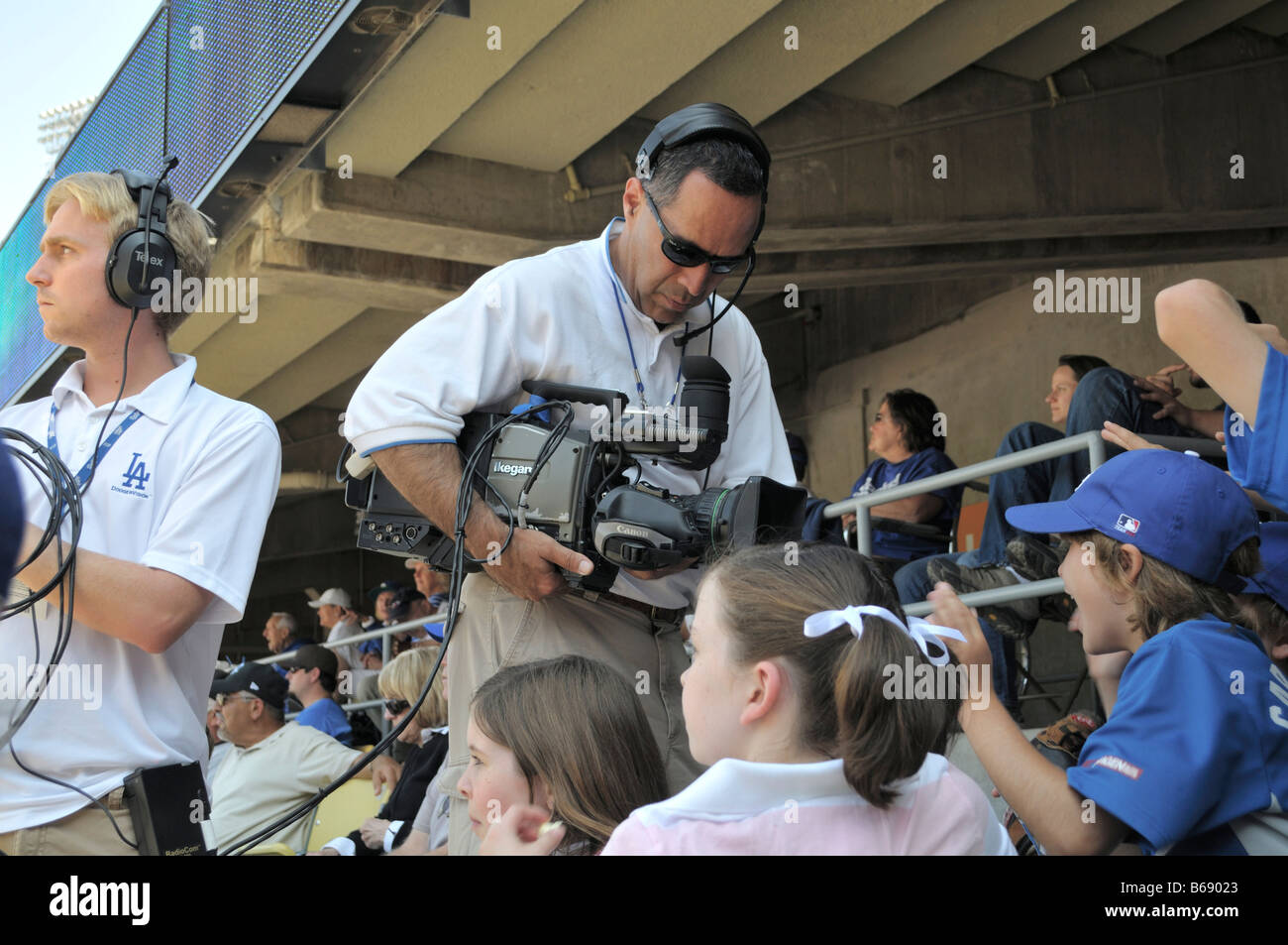 Video camera crew transmitting images of excited young baseball fans ...
