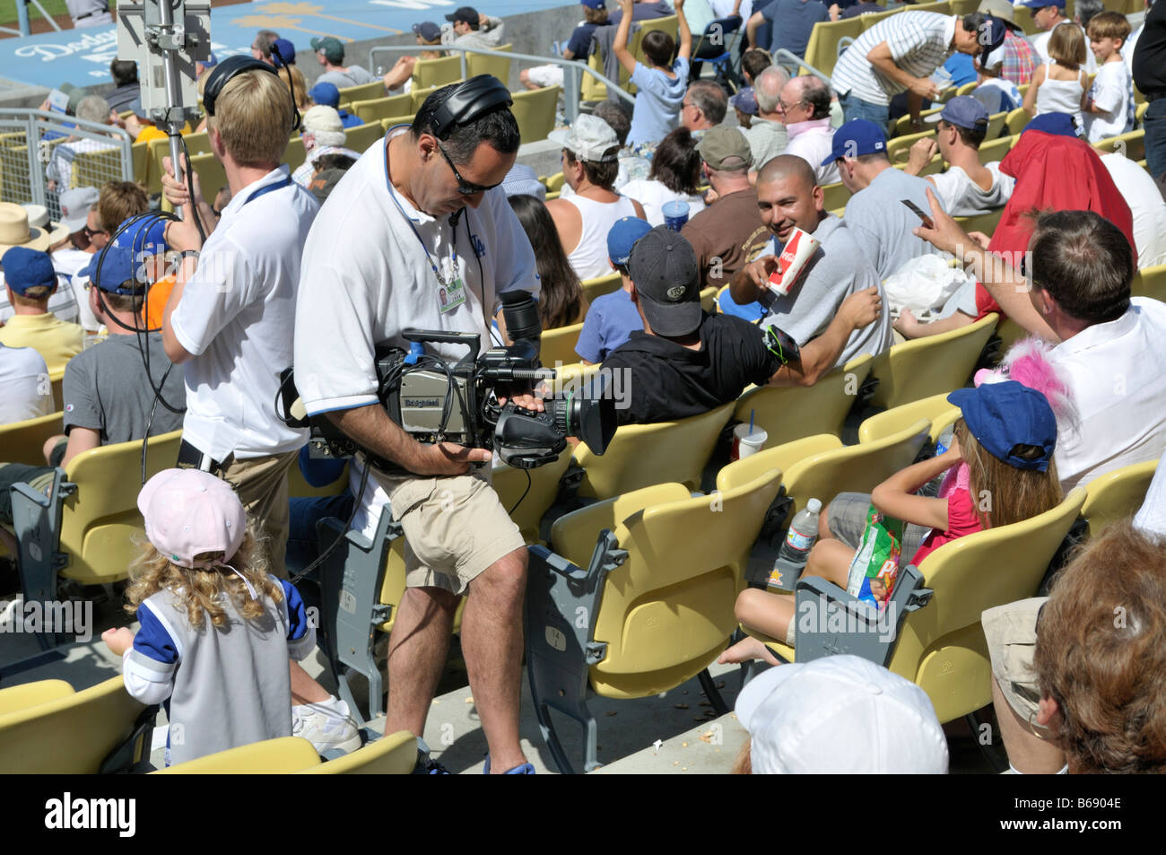 Video camera crew transmitting images of excited young baseball fans ...