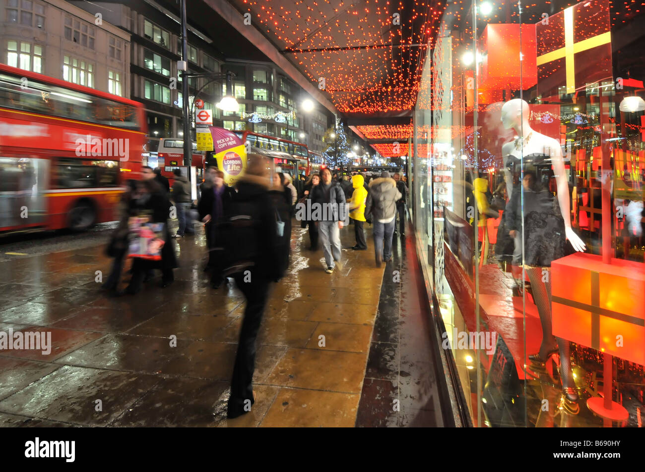 Shoppers on wet pavement outside department store front window Xmas ...
