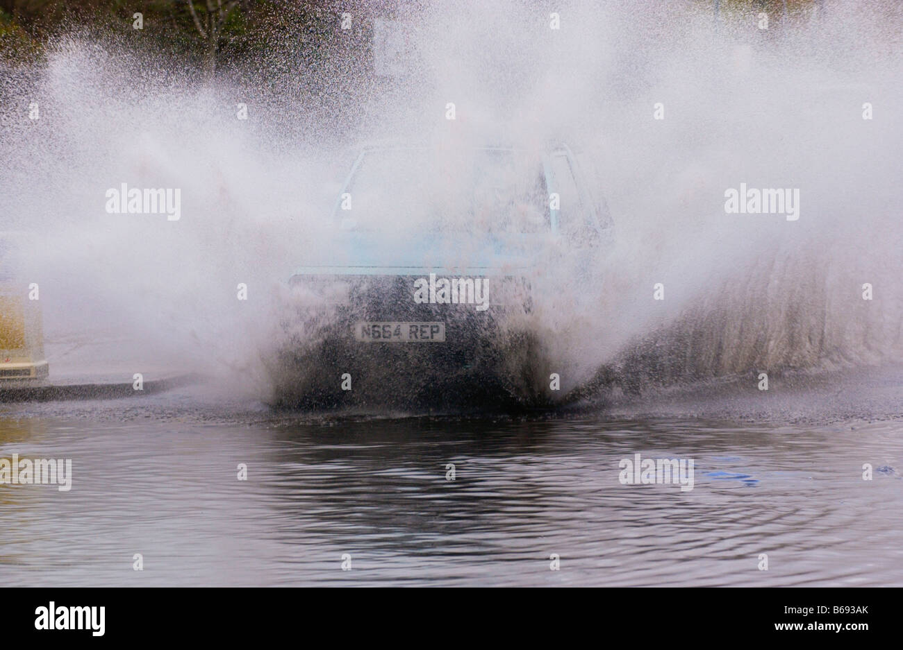 Cars drive through flood water splash after road flooded by heavy rain ...