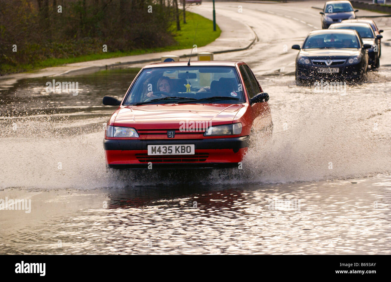 Cars drive through flood water splash after road flooded by heavy rain ...