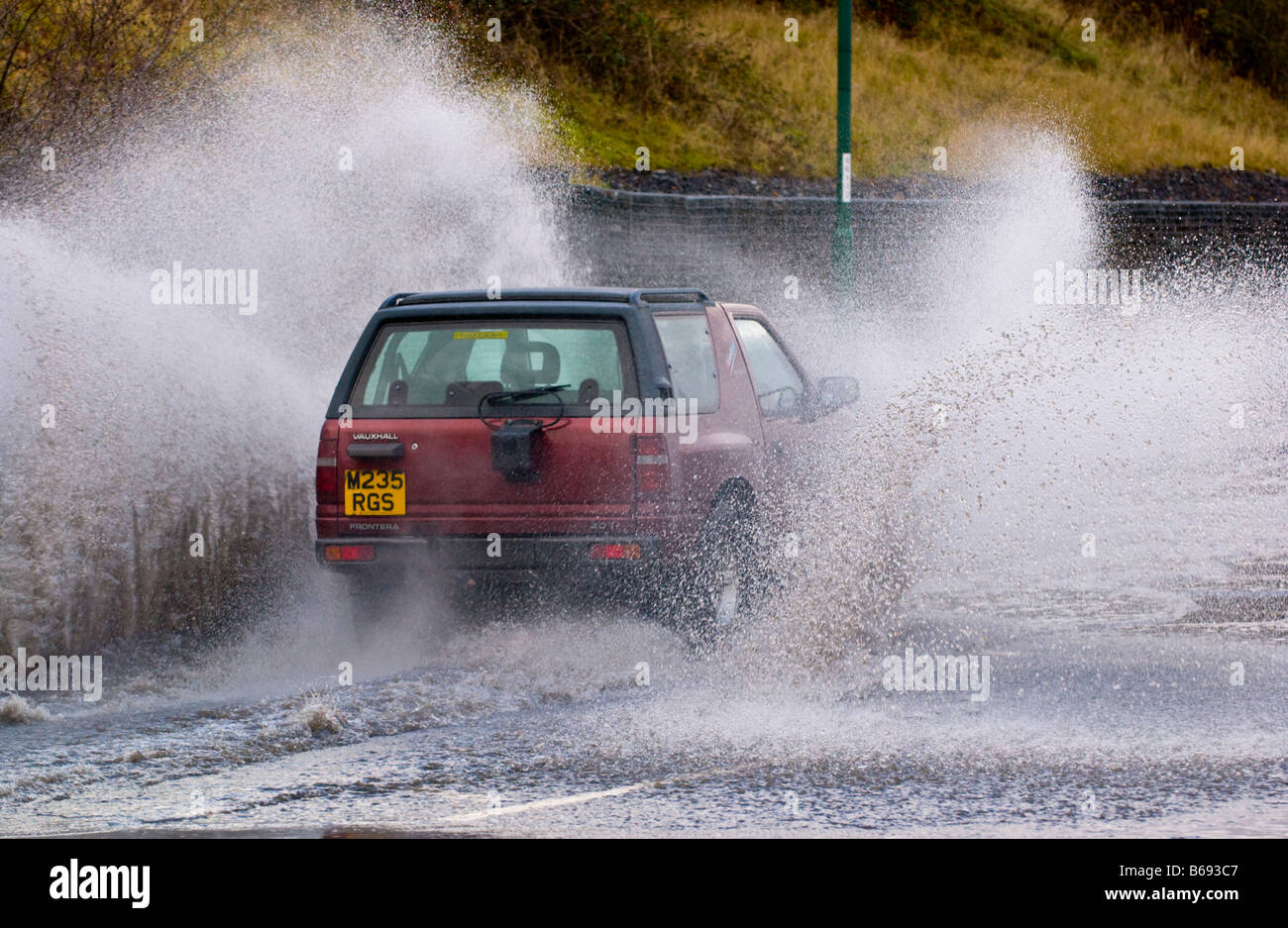 Cars drive through flood water splash after road flooded by heavy rain ...