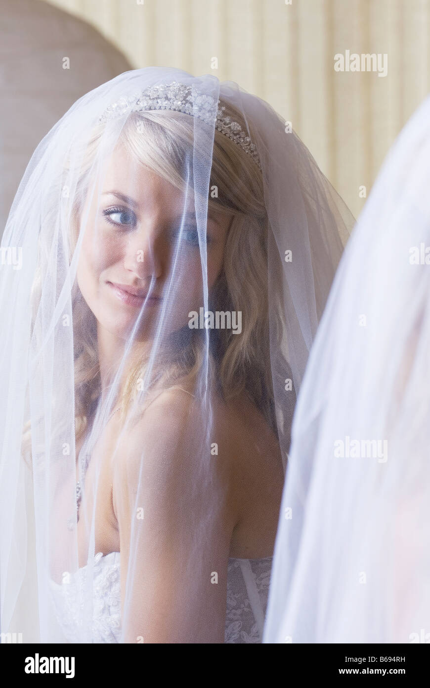 Bride wearing veil looking at herself in mirror Stock Photo - Alamy