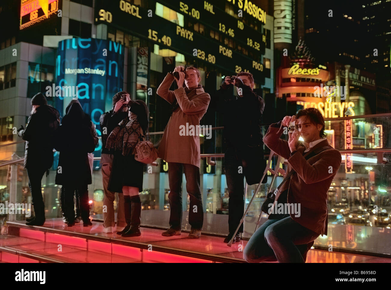 Broadway lights blaze behind tourists as they take pictures of Times ...