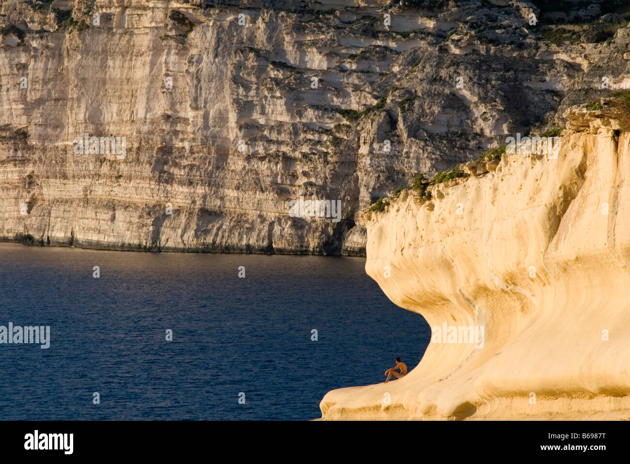 Limestone cliff eroded into a wave by the wind at Xlendi Bay in the ...