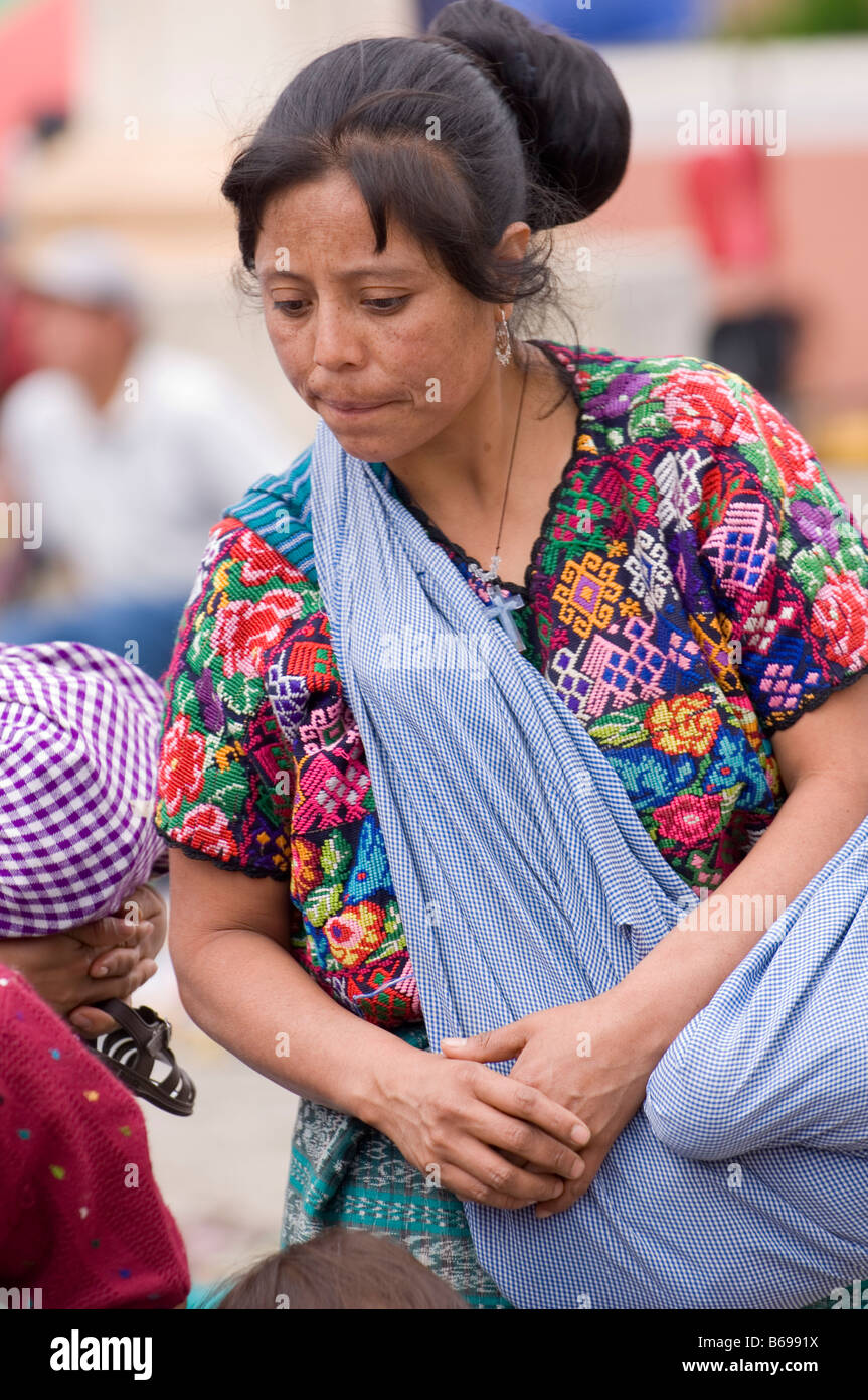 Indigenous woman carrying child in scarf in colourful traditional dress ...