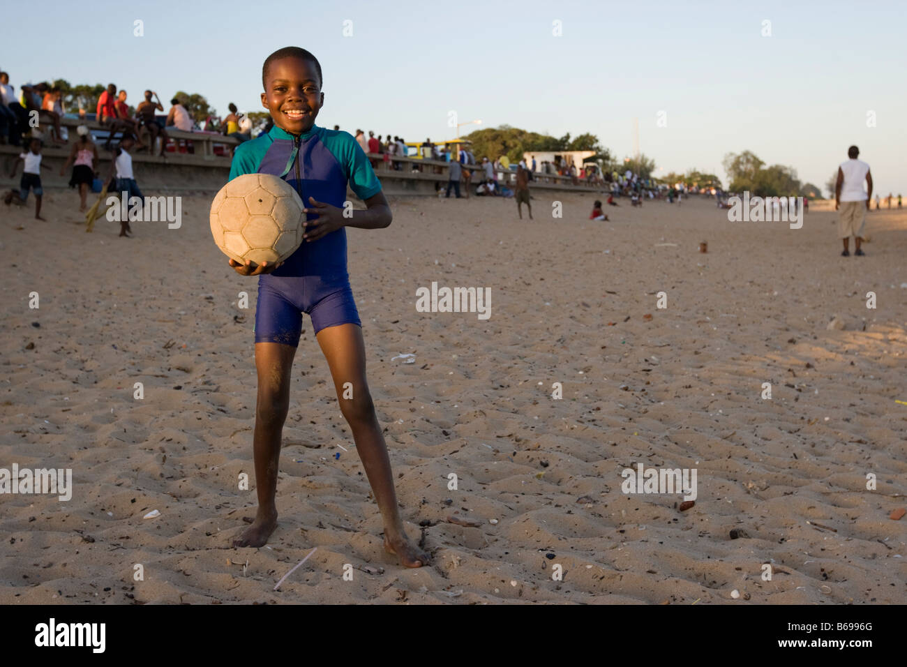 Africa Mozambique Maputo Portrait of young boy playing with volleyball on crowded beach at ...