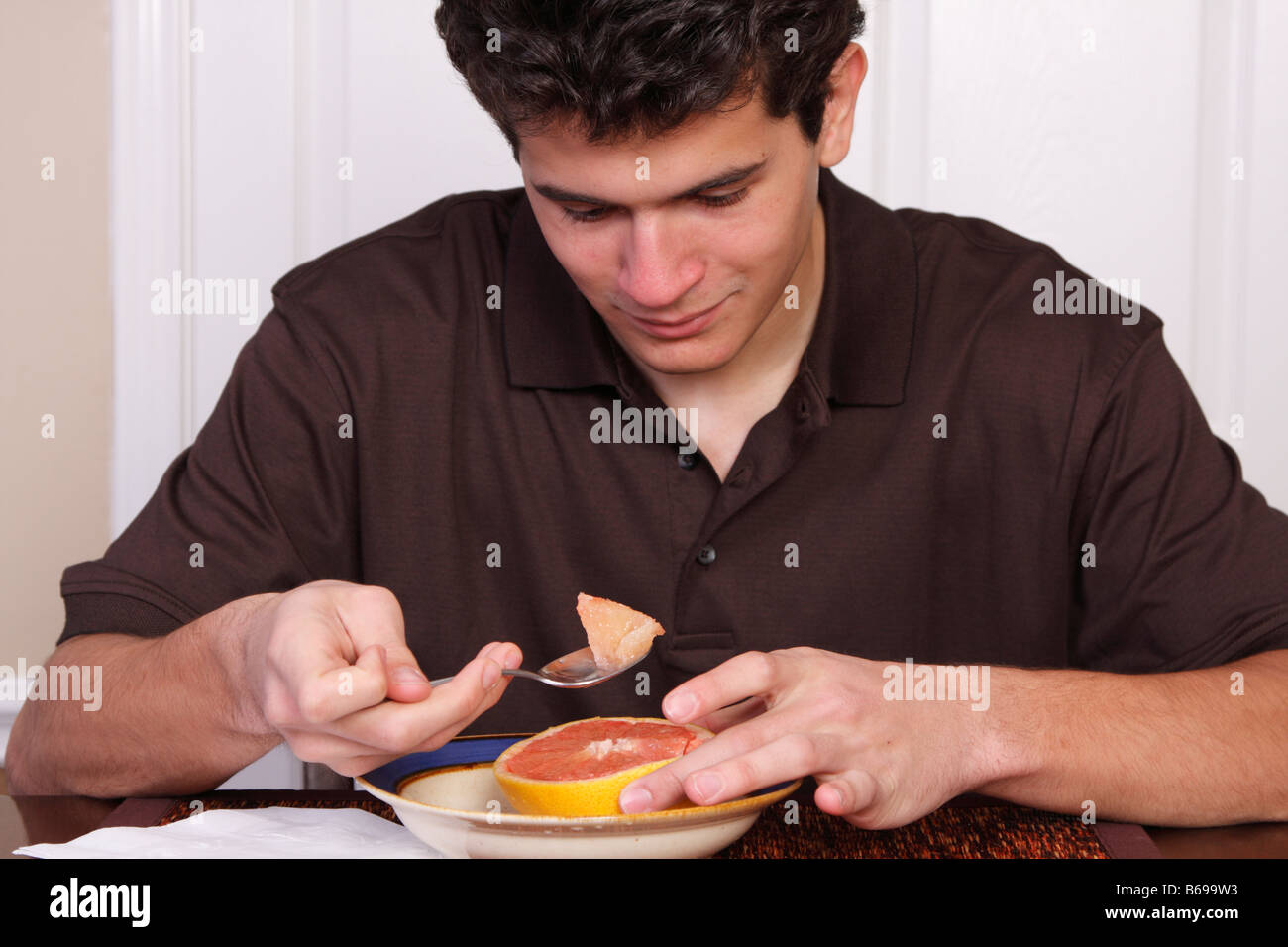 teen eating a grapefruit for breakfast Stock Photo - Alamy