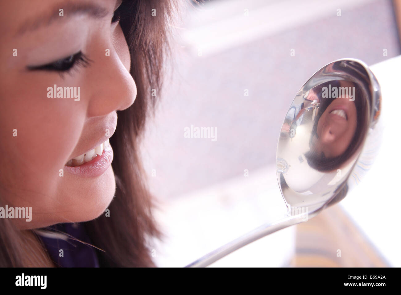 teen looking at her reflection in a spoon Stock Photo - Alamy