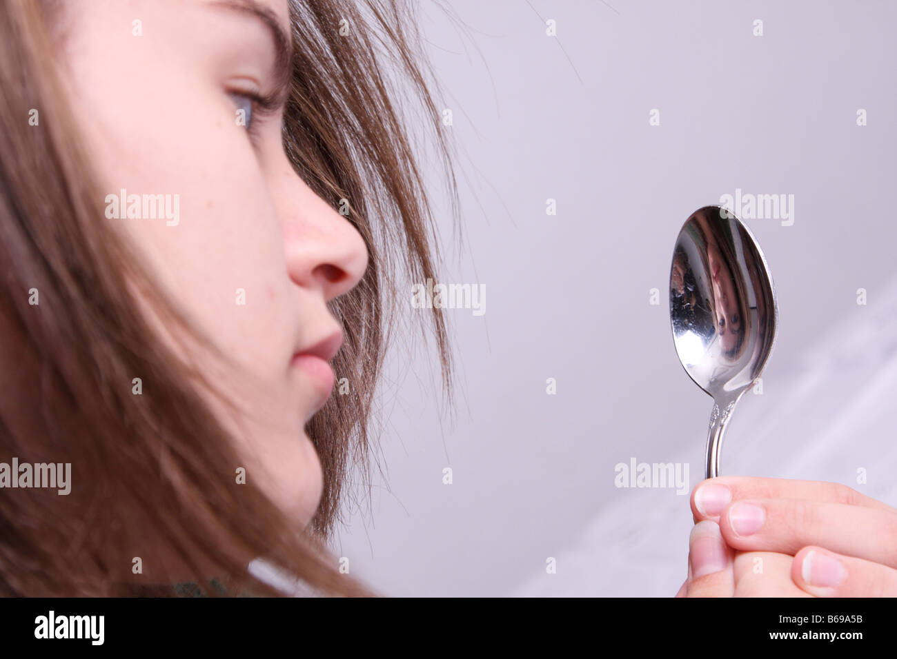 teen looking at her reflection in a spoon Stock Photo - Alamy