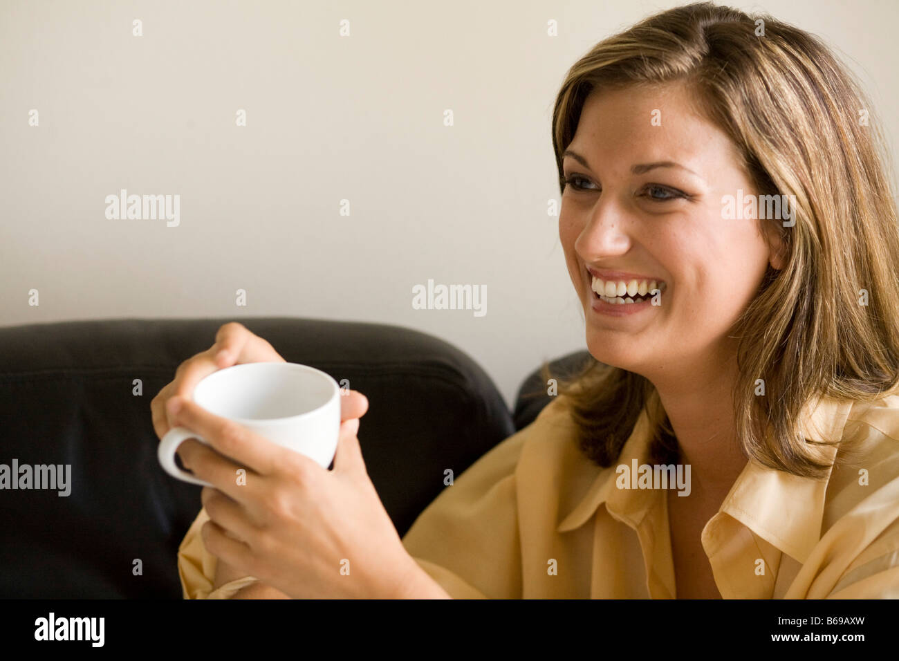 Young woman sitting on couch portrait Stock Photo - Alamy