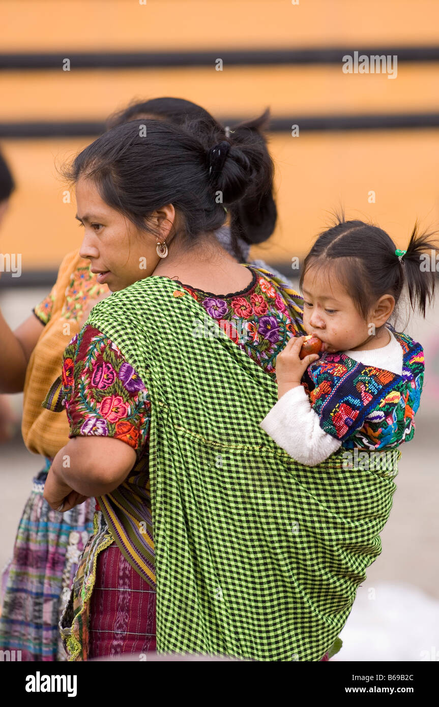 Indigenous woman carrying child in scarf in colourful traditional dress ...