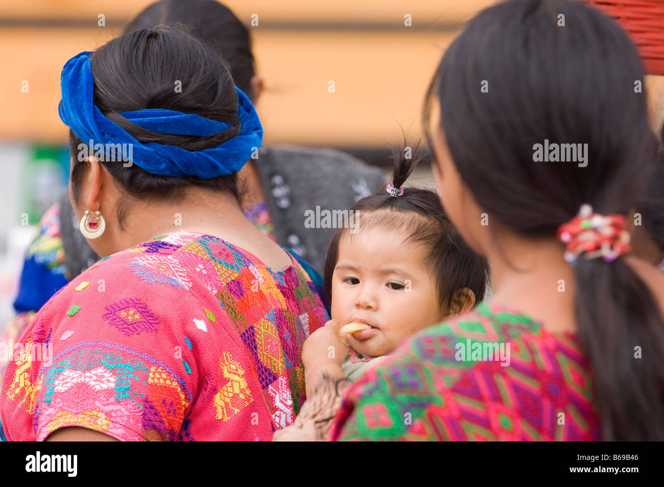 Indigenous woman carrying child in scarf in colourful traditional dress ...