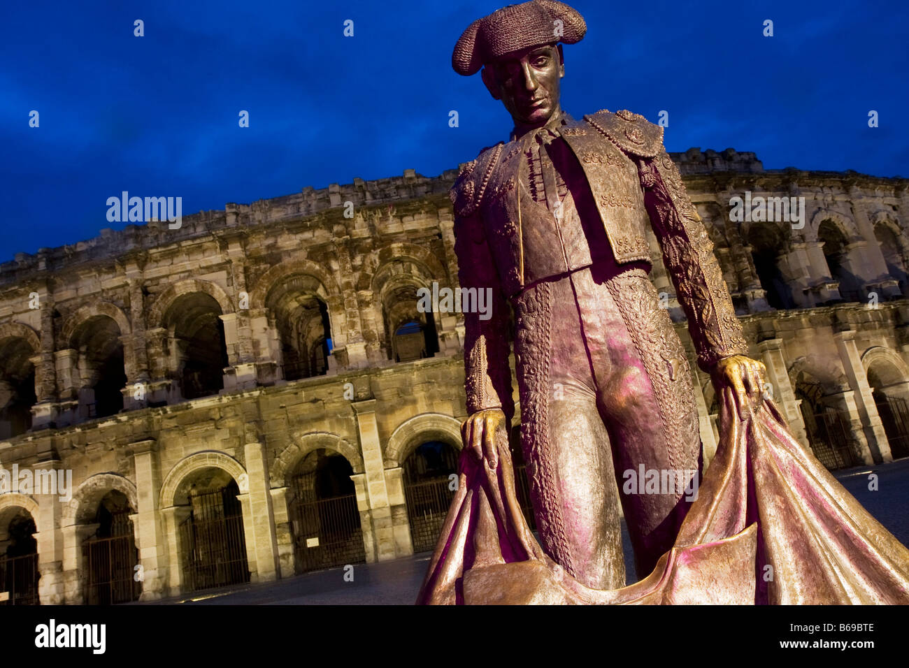 Statue of Bullfighter in front of Arena in french city Nimes at dusk ...