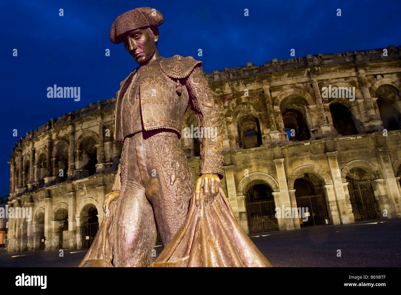 Statue of Bullfighter in front of Arena in french city Nimes at dusk ...