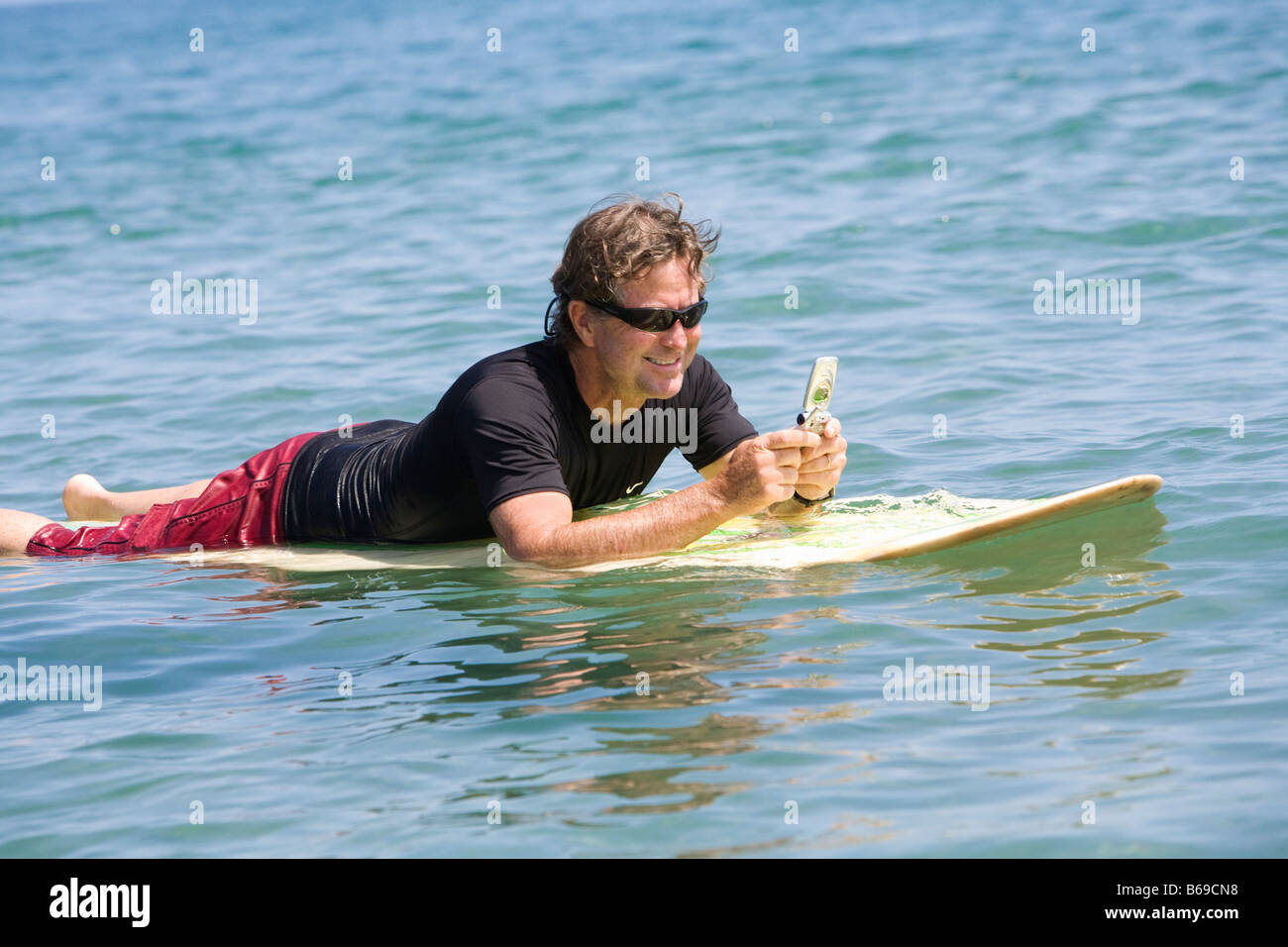 Man floating on water and text messaging Stock Photo - Alamy