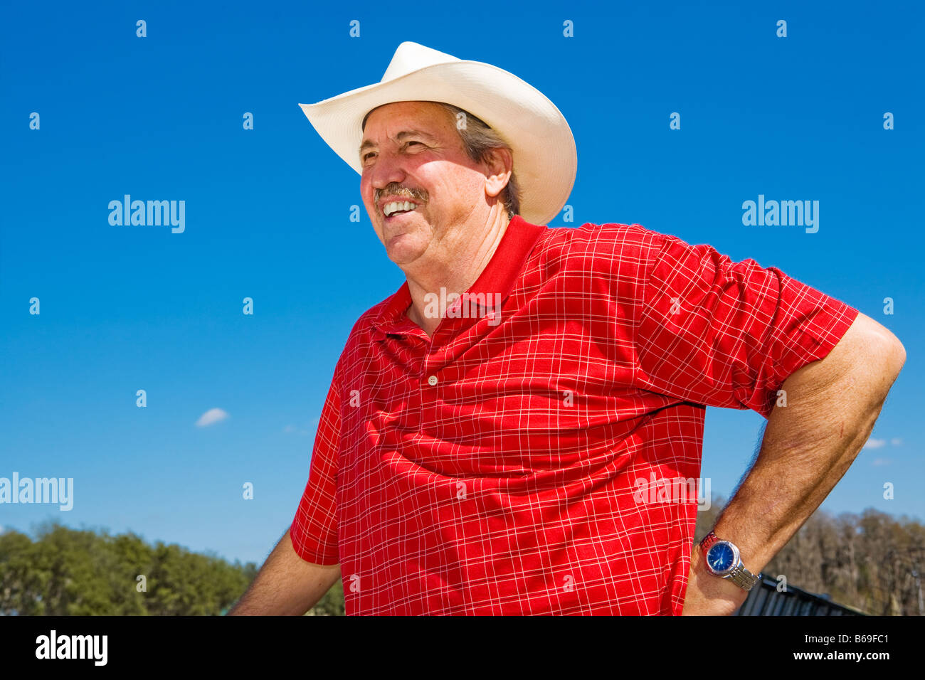 Handsome mature cowboy laughing against a blue sky with room for text ...