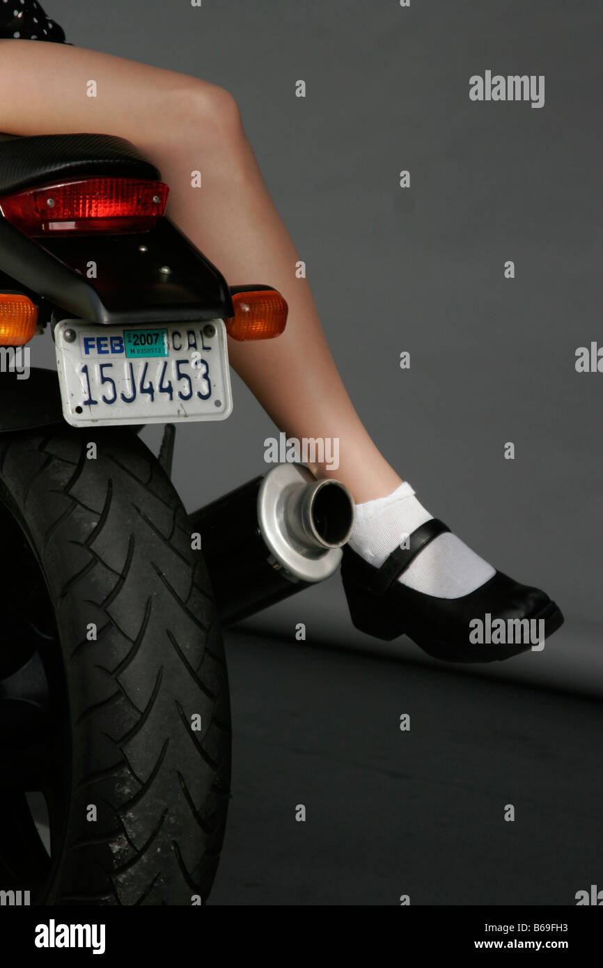 woman's leg draped over a high end sport motorcycle. She is wearing ...