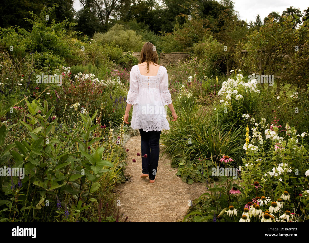 A female walking through a garden Stock Photo - Alamy