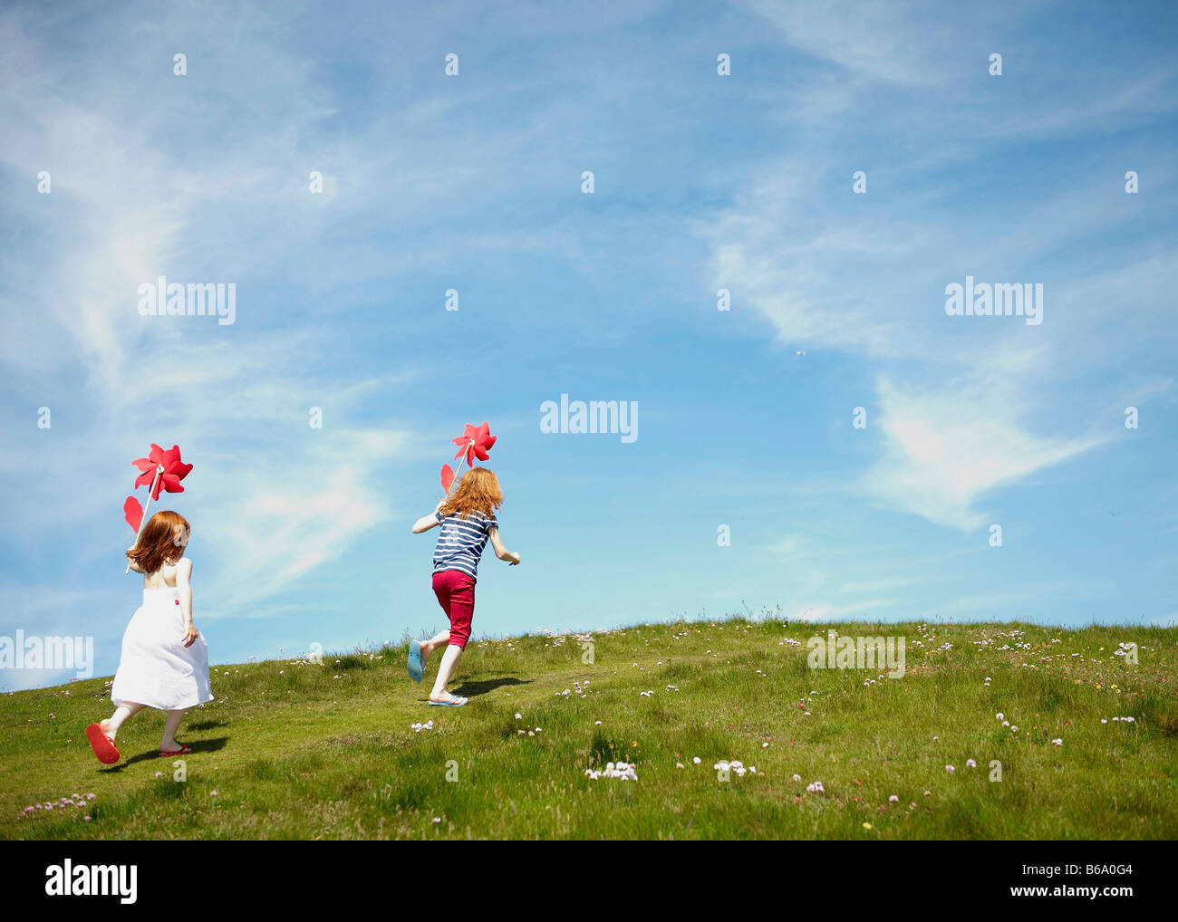 2 girls running in field with windmills Stock Photo - Alamy