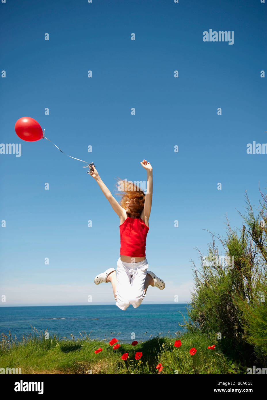 Young girl jumping with red balloon Stock Photo - Alamy