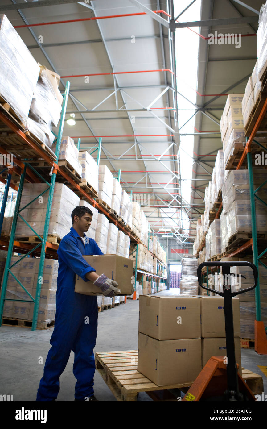 Worker stacking boxes in warehouse Stock Photo - Alamy