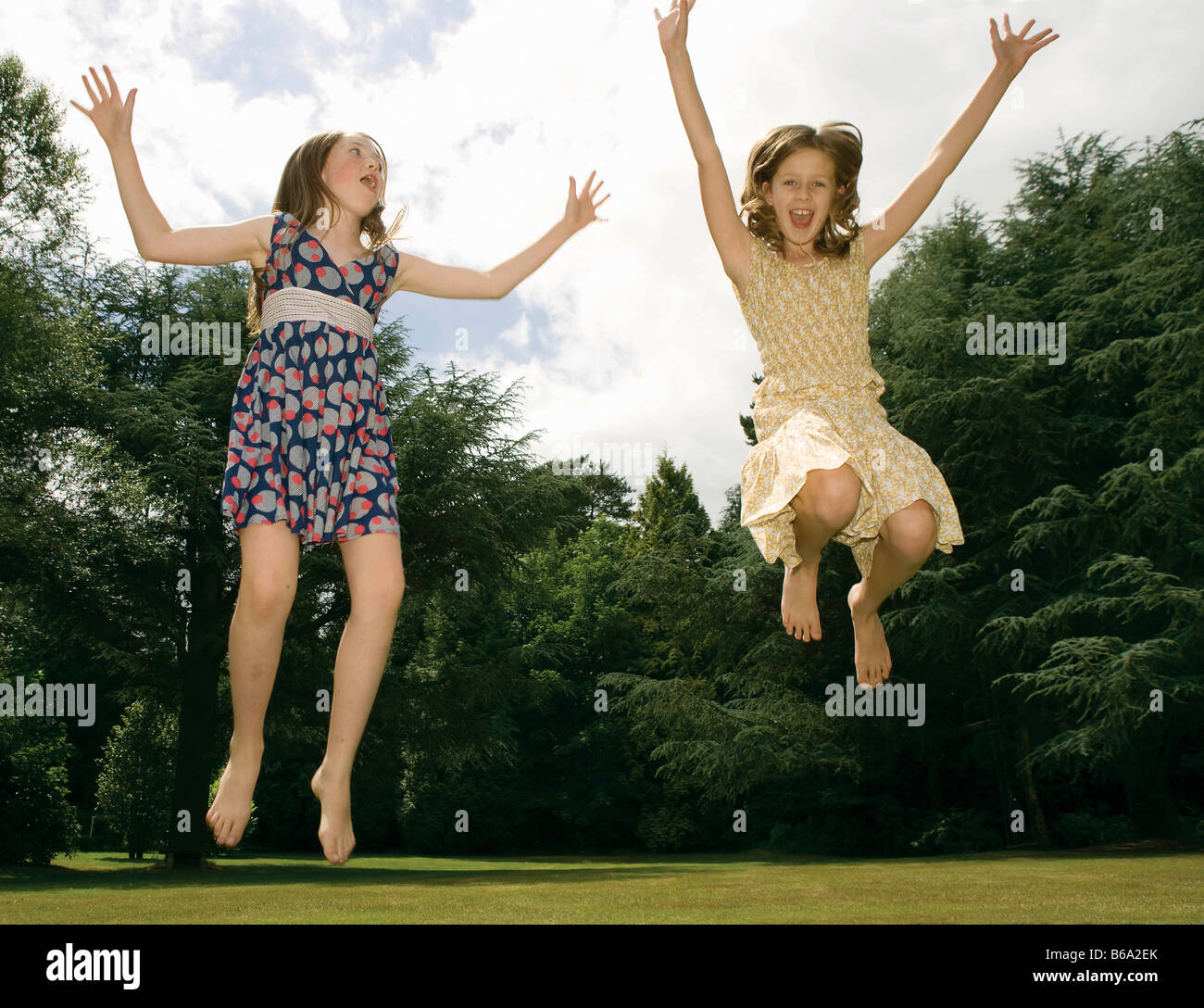 Girls jumping in garden Stock Photo - Alamy