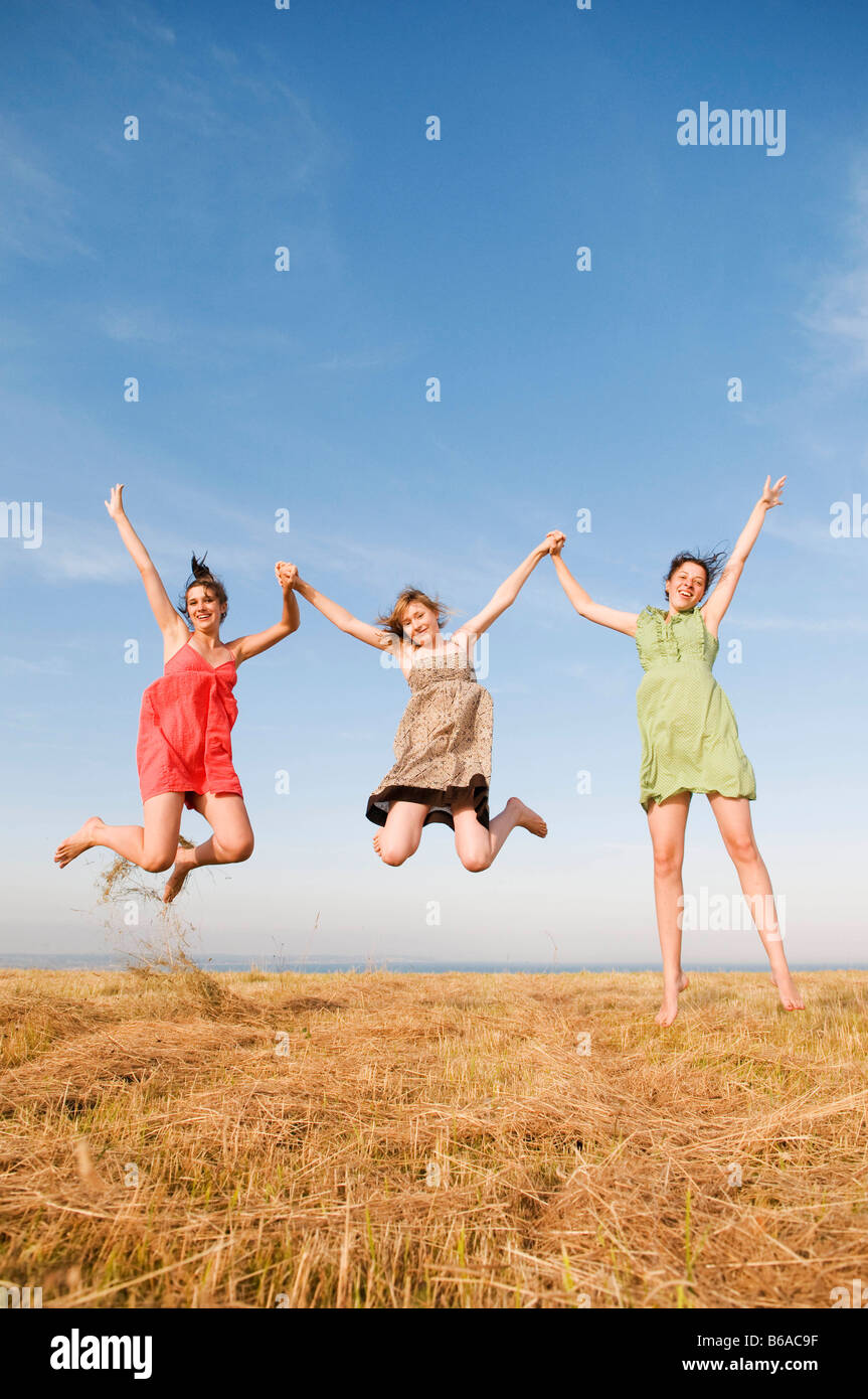 Three girls jump and hold hands up high Stock Photo - Alamy