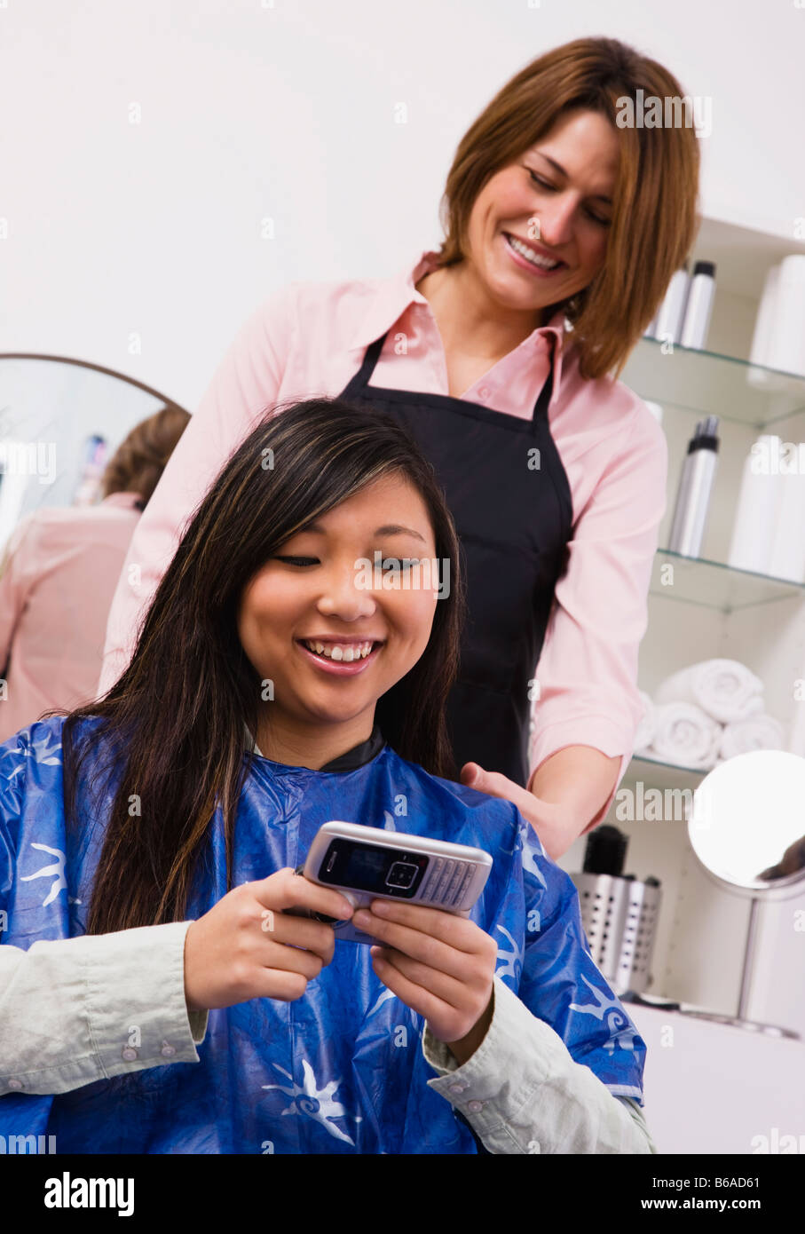 Woman getting haircut and texting with cell phone Stock Photo - Alamy