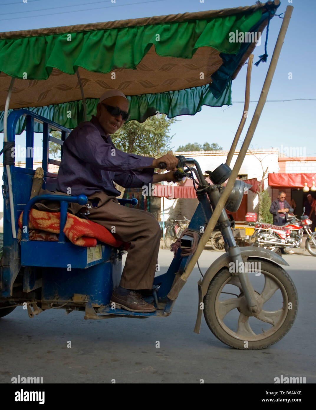 Autorickshaw driver touring with his motorbike with a funny canopy ...