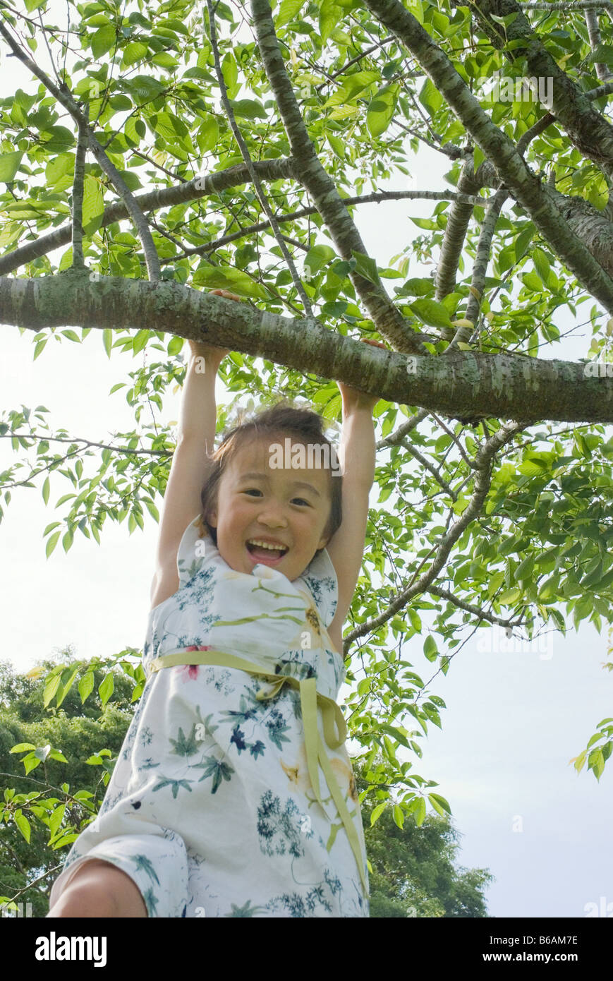 Girl hanging from tree Stock Photo - Alamy