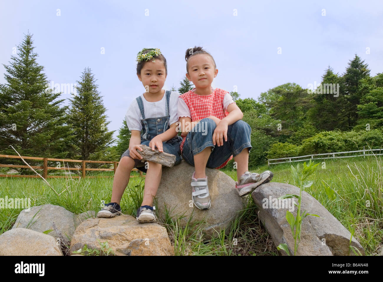 Two girls sitting on rock Stock Photo - Alamy