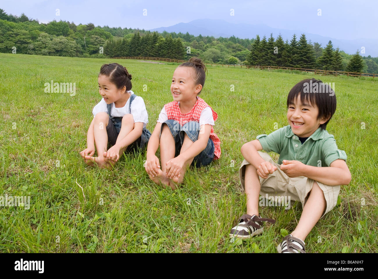 Children sitting on grass field Stock Photo - Alamy