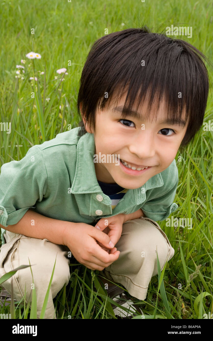 Boy crouching on grass field Stock Photo - Alamy