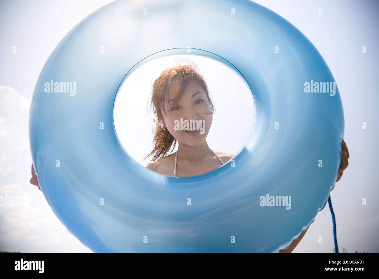 Young woman looking through inner tube Stock Photo - Alamy