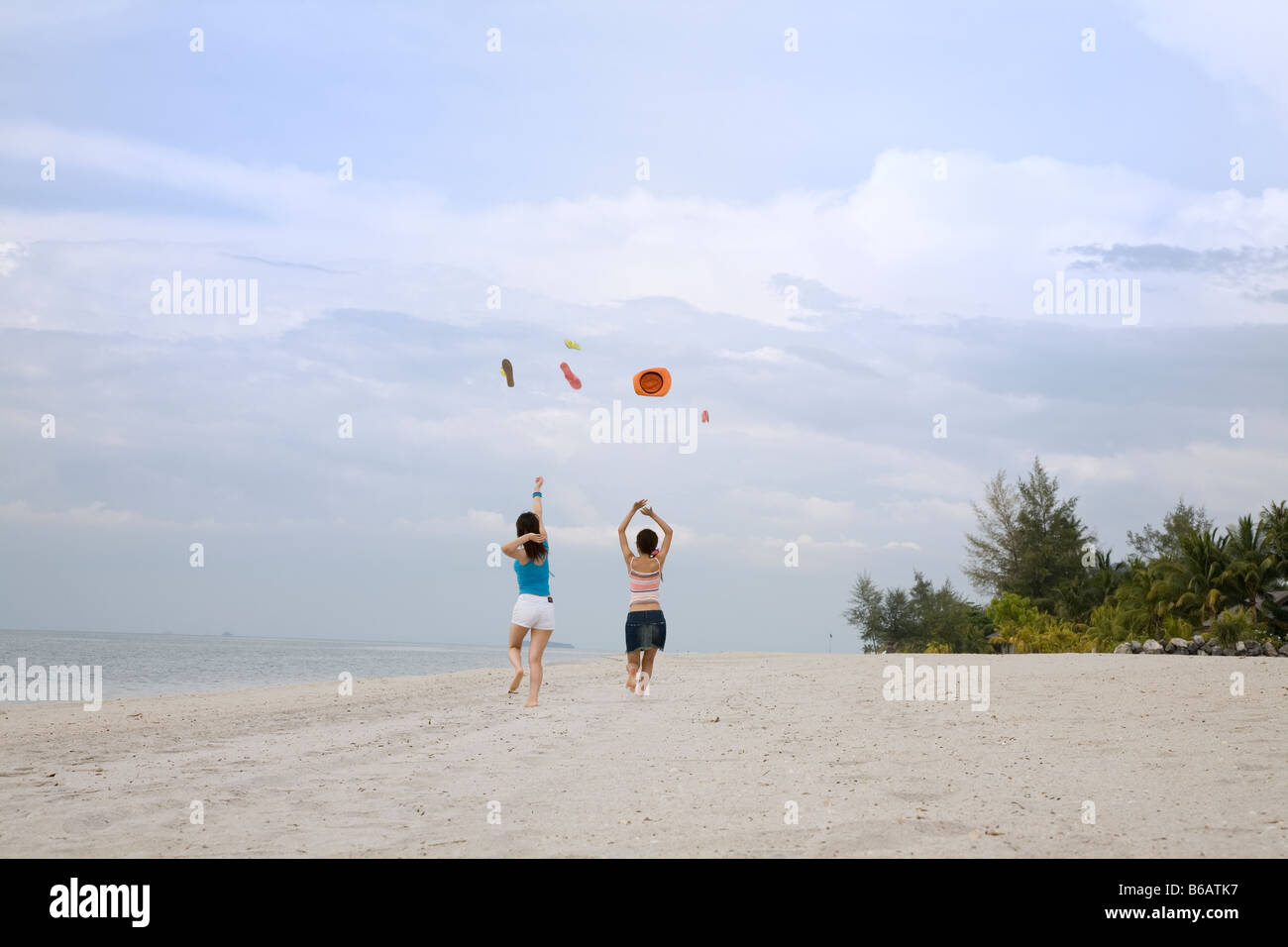 Two young women throwing flip flop and hat Stock Photo - Alamy