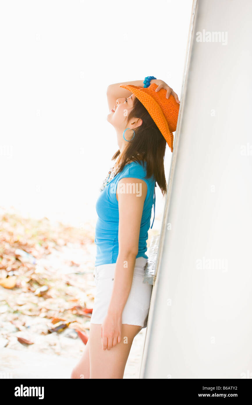 Young woman leaning against wall Stock Photo - Alamy