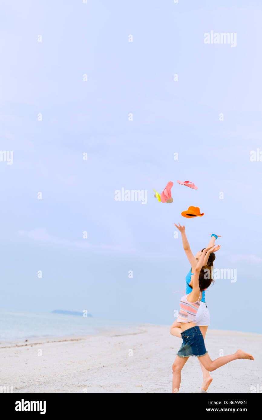 Two young women throwing flip flop and hat Stock Photo - Alamy