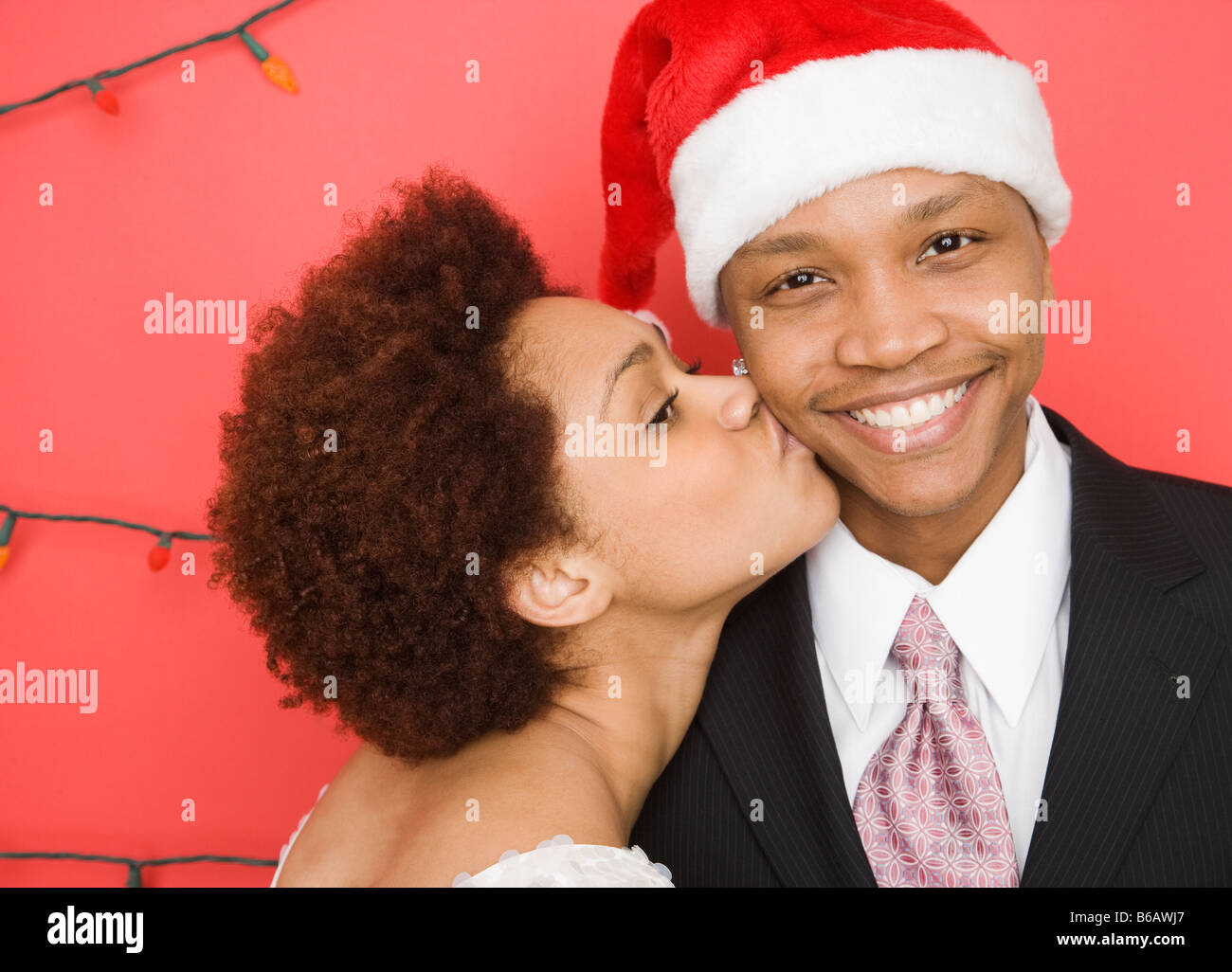 Mixed race woman kissing boyfriend in santa hat Stock Photo - Alamy