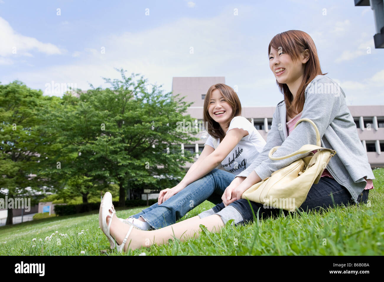 Young women sitting on lawn Stock Photo - Alamy